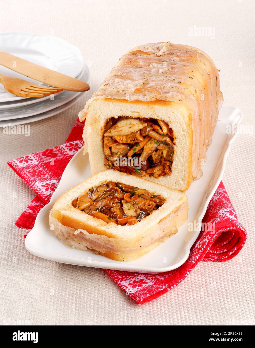A loaf of bread wrapped in bacon with a mushroom filling Stock Photo ...