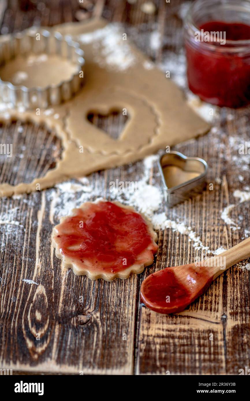Jam being spread onto unbaked vegan shortbread biscuits Stock Photo - Alamy