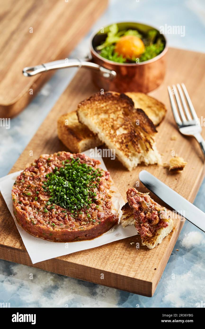 Beef tartare with toasted bread and salad Stock Photo - Alamy