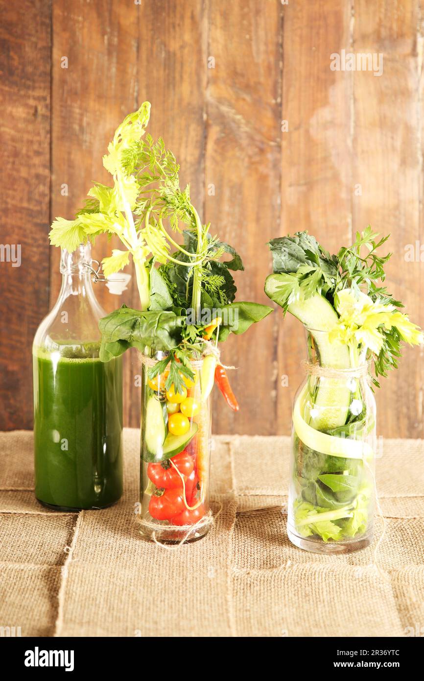 Healthy mixed vegetable juice with ingredients in glasses and a bottle ...