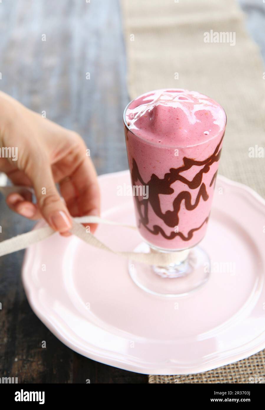 A raspberry and chocolate smoothie in a glass being decorated with ...