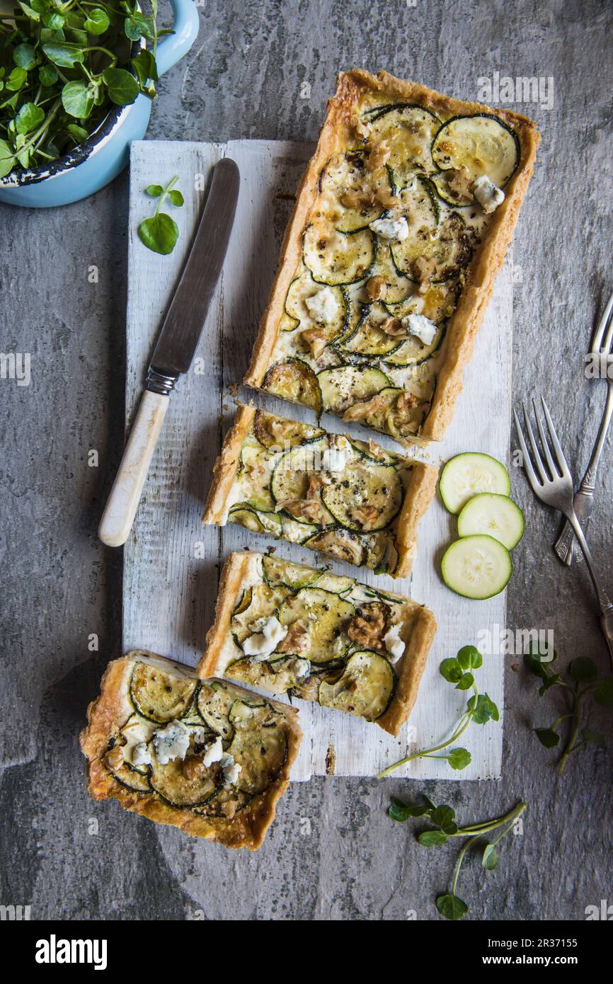 Savoury blue cheese and courgette tart topped with walnuts, sliced ...