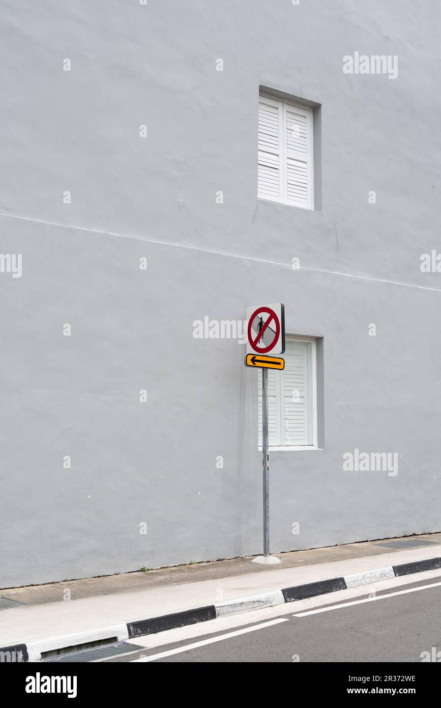 Gray wall and sidewalk, traffic sign arrow in Singapore Stock Photo - Alamy