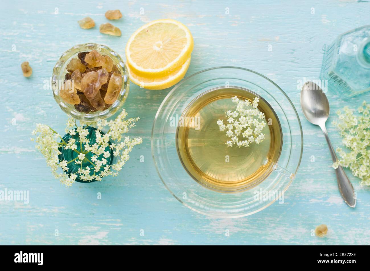 Elderflower tea in a cup, elderflowers, lemon slices and rock sugar ...
