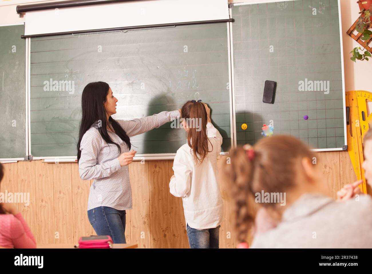 Teacher helping pupil at blackboard Stock Photo - Alamy