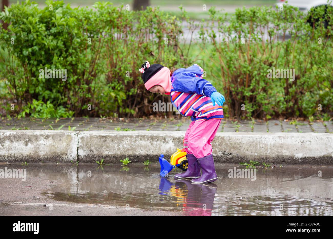 Little girl playing in the puddle Stock Photo - Alamy