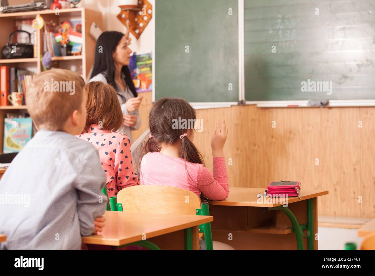 Teacher helping pupil at blackboard Stock Photo - Alamy