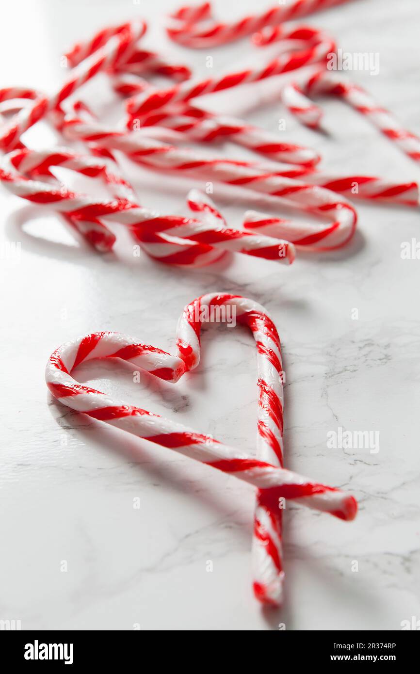 White marble surface covered in candy canes and two canes in the ...