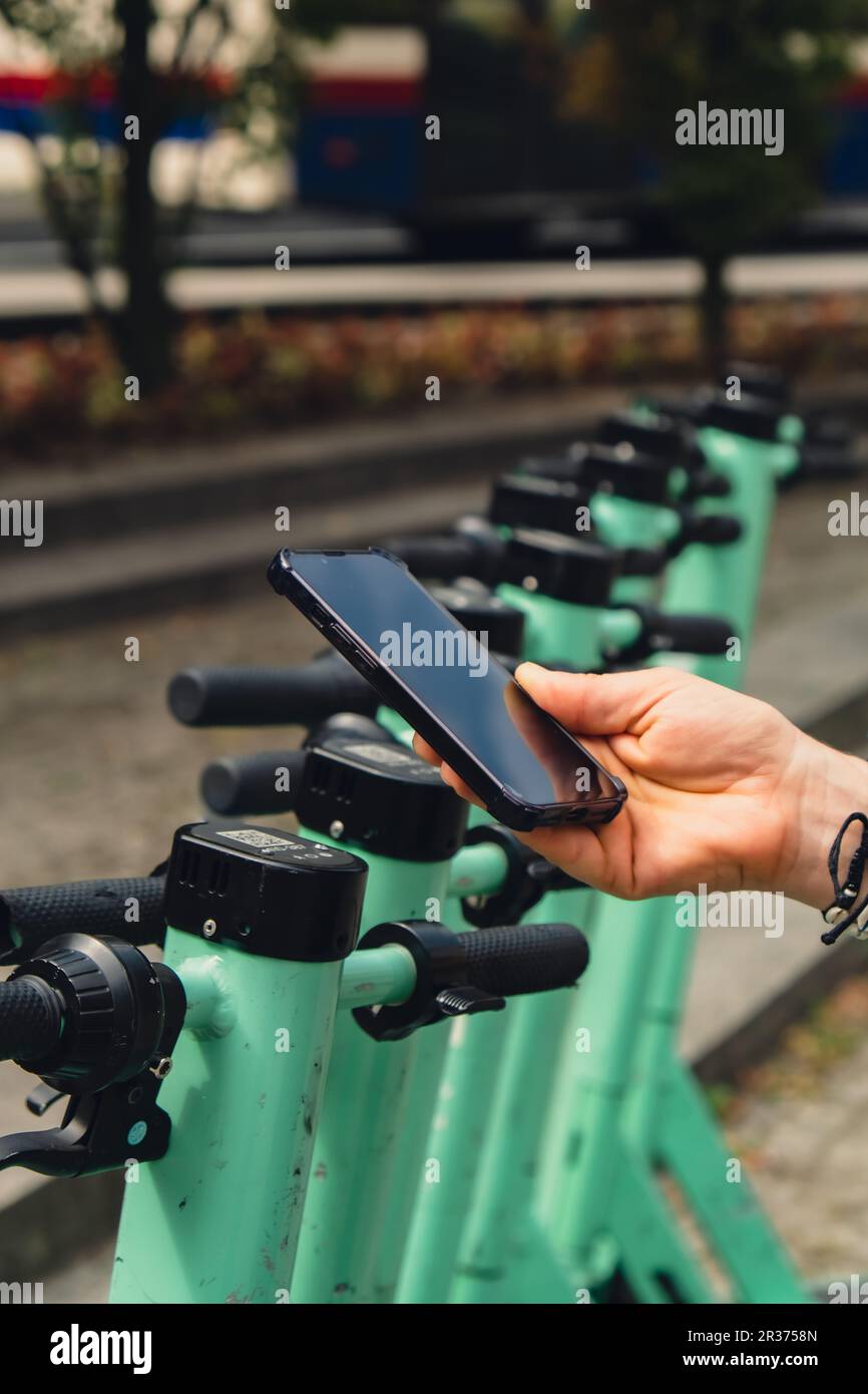 Female hand uses mobile phone to scan QR code on Electric scooter on ...