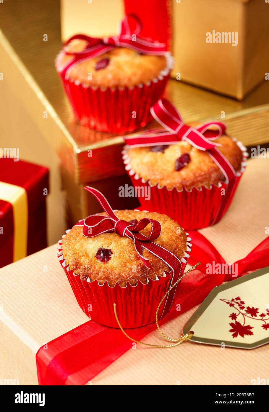 Three Festive cranberry and marzipan muffins tied with ribbon sitting ...