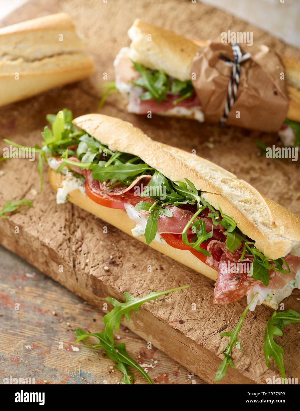 Rustic baguette with serrano ham, salami, rocket and tomato Stock Photo ...