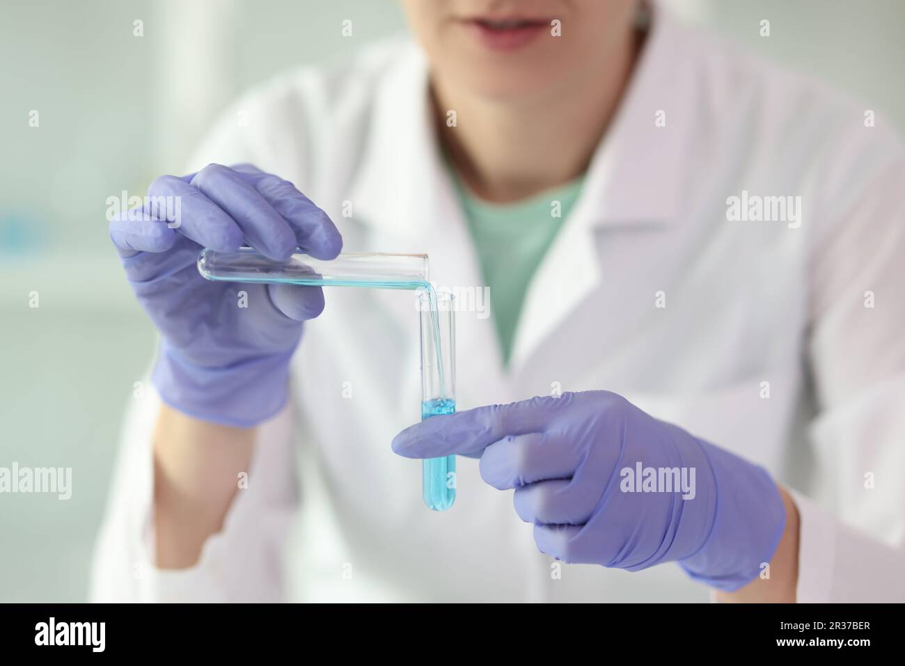 Female laboratory assistant pours blue liquid from test tube Stock ...