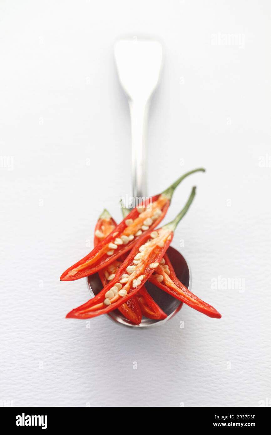 Fresh sliced red chili peppers on a silver spoon with a white ...