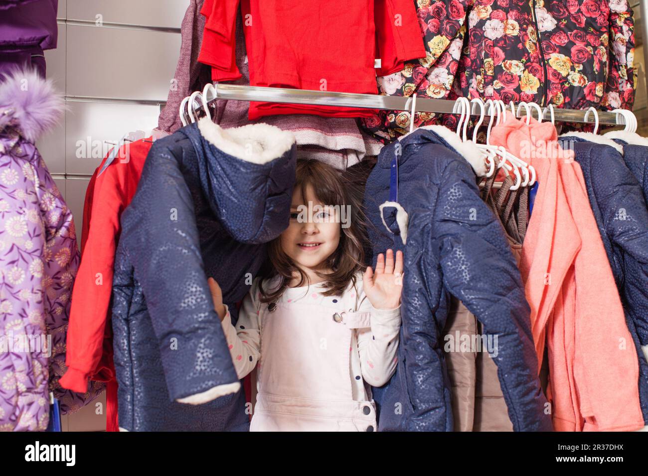 The little girl having fun in clothing store Stock Photo - Alamy