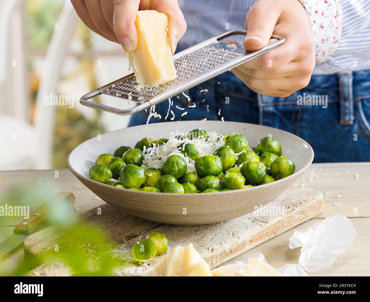 A man grating cheese over brussel's sprouts Stock Photo - Alamy