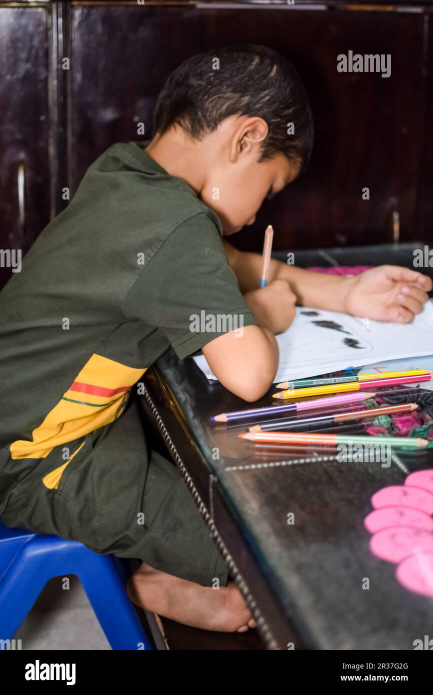 Smart Indian little boy drawing with colourful pencils kit of various ...