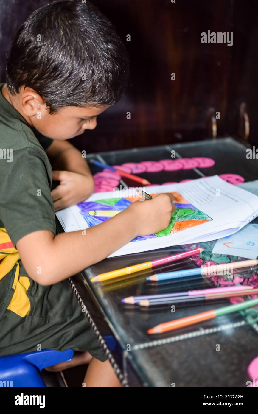 Smart Indian little boy drawing with colourful pencils kit of various ...
