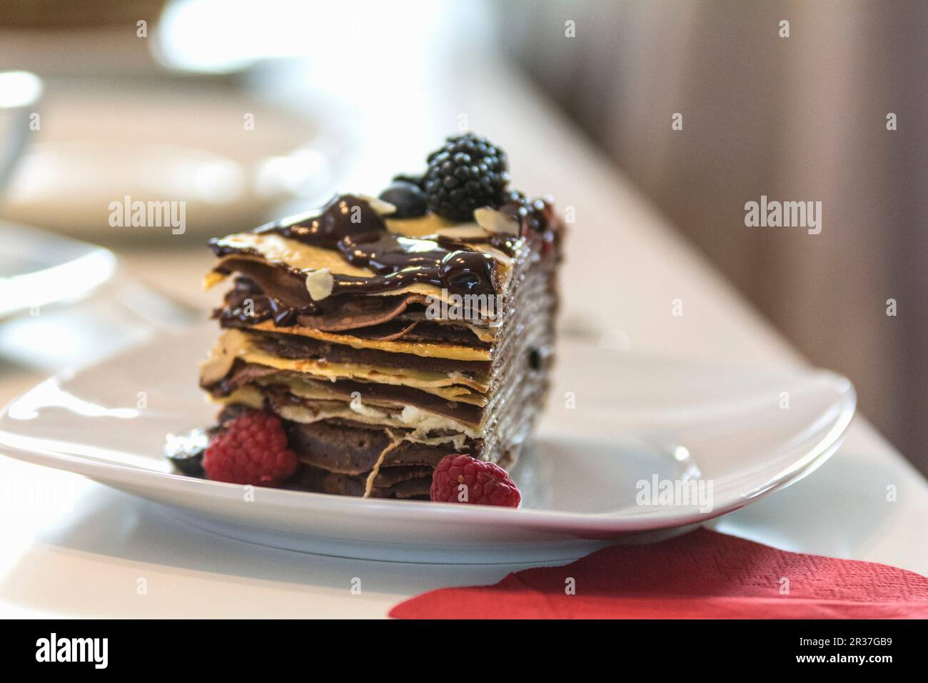 A slice of pancake cake with berries and chocolate sauce Stock Photo ...