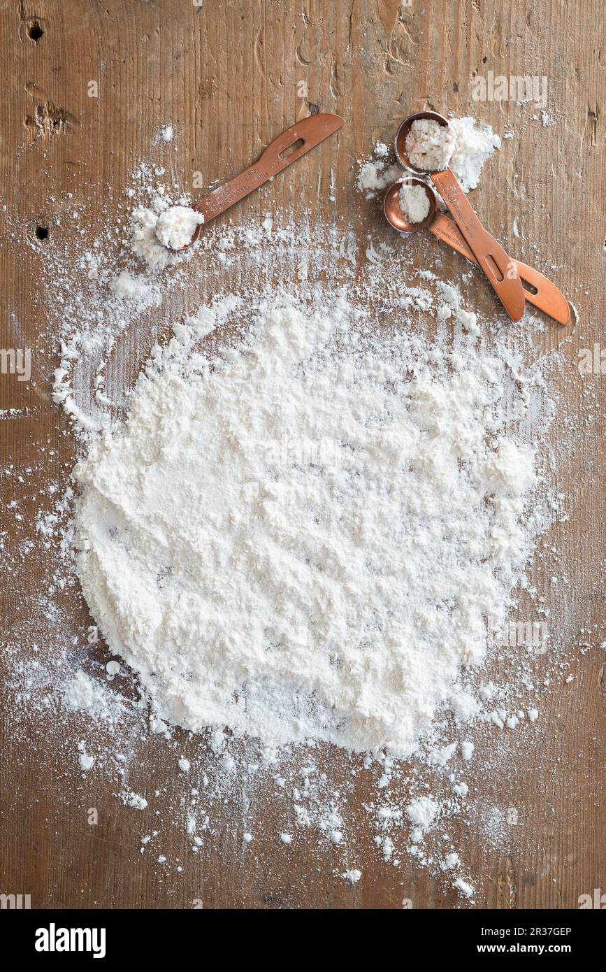 A flour-covered wooden board with flour with measuring spoons Stock ...