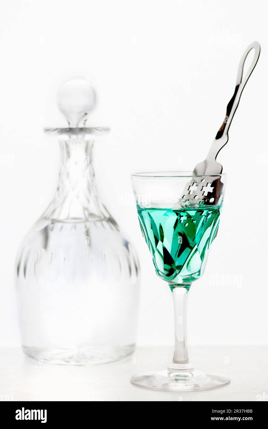 Absinthe with an absinthe spoon in a crystal glass in front of a ...
