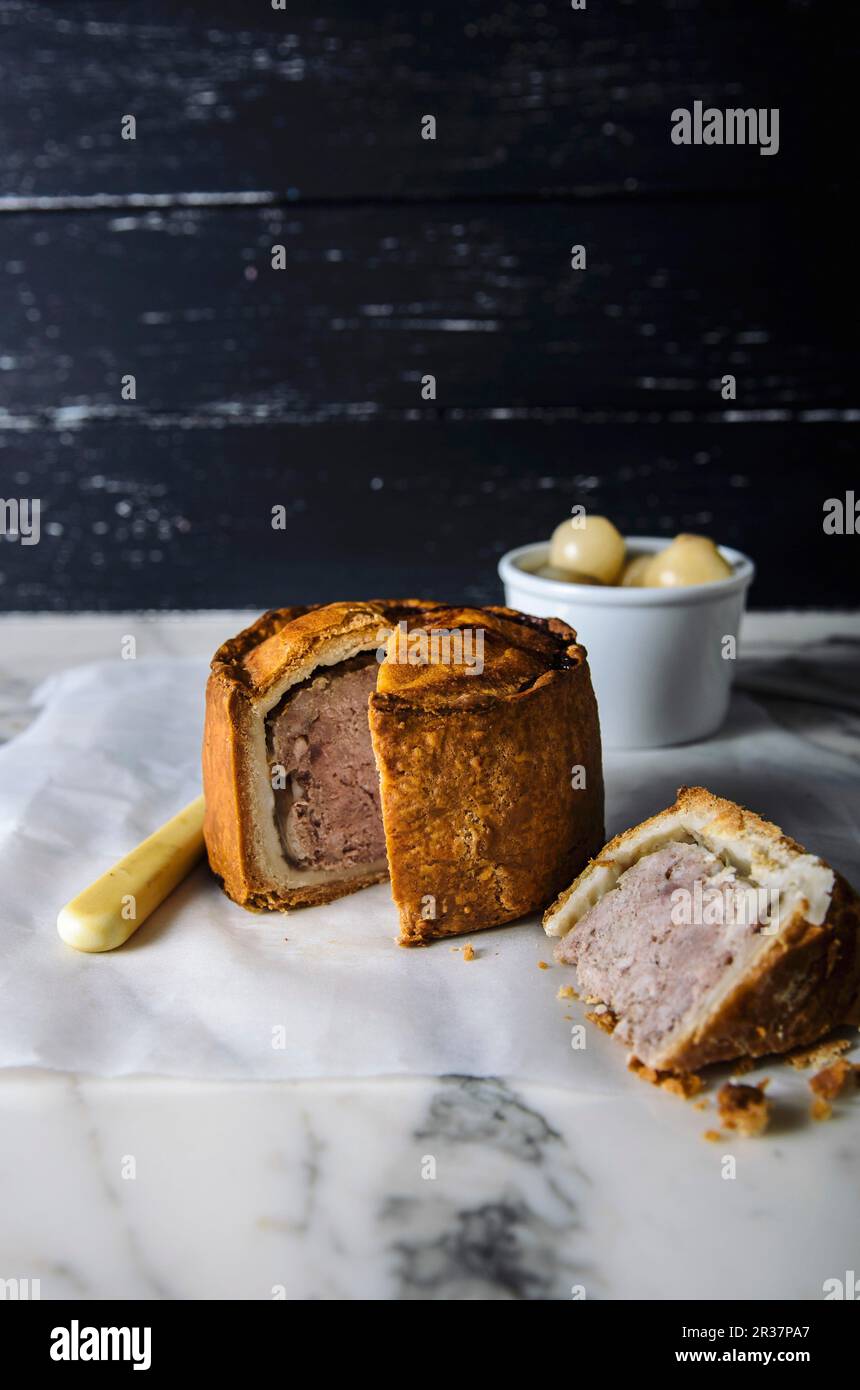Pork pie (pastry with pork), cut on a marble board Stock Photo - Alamy