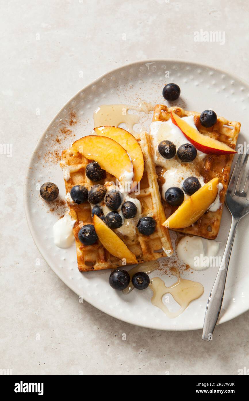 Belgian waffles with yoghurt, honey, blueberries and peach wedges Stock ...