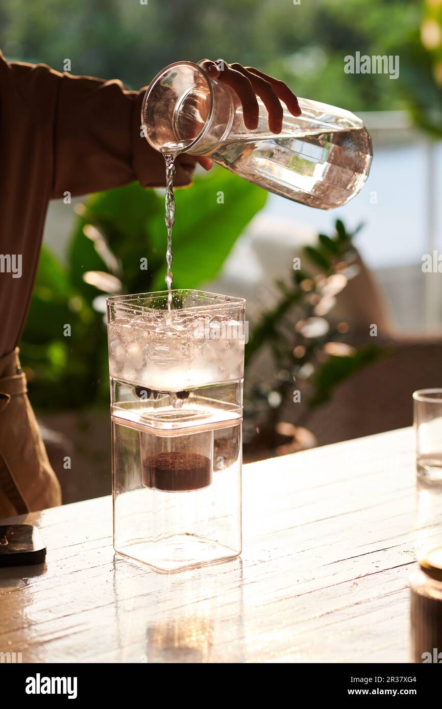 Barista pouring fresh water in cold brew coffee maker Stock Photo - Alamy