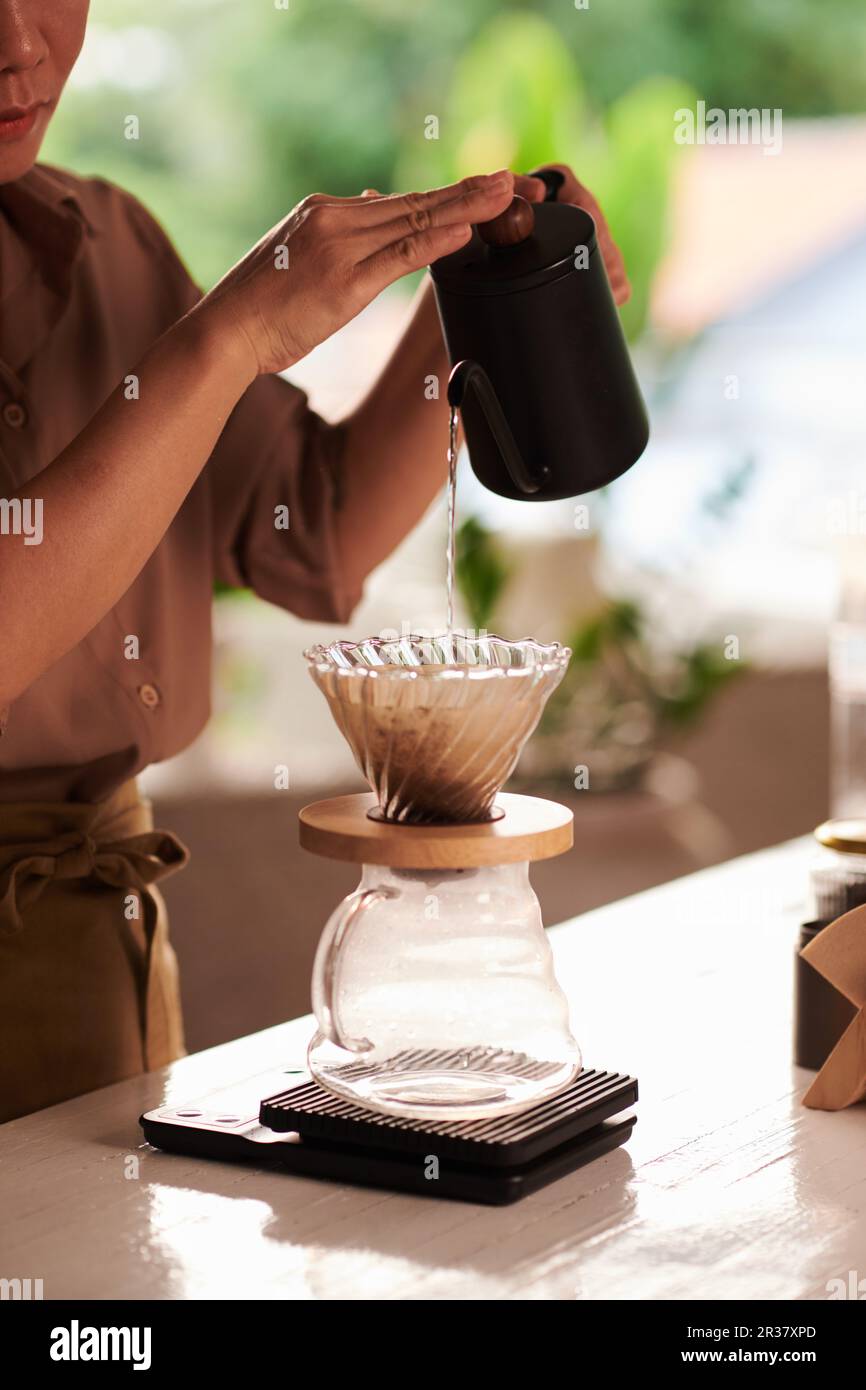 Cafe worker pouring hot water in dipper with paper funnel Stock Photo ...