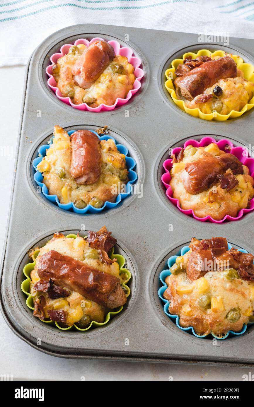 A metal muffin tray with savoury Frankfurter sausage muffins in ...