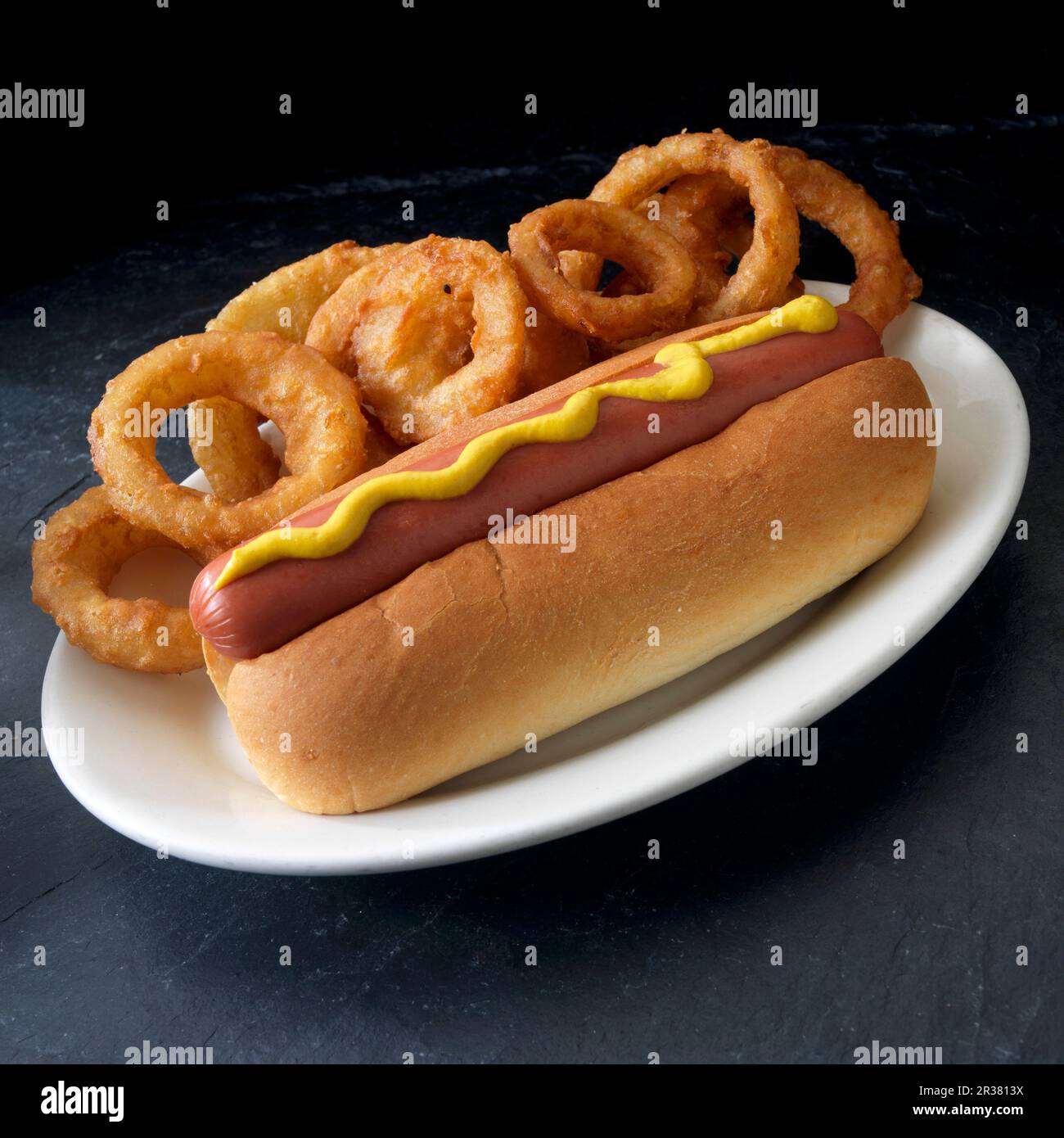 A hot dog with mustard and onion rings Stock Photo - Alamy