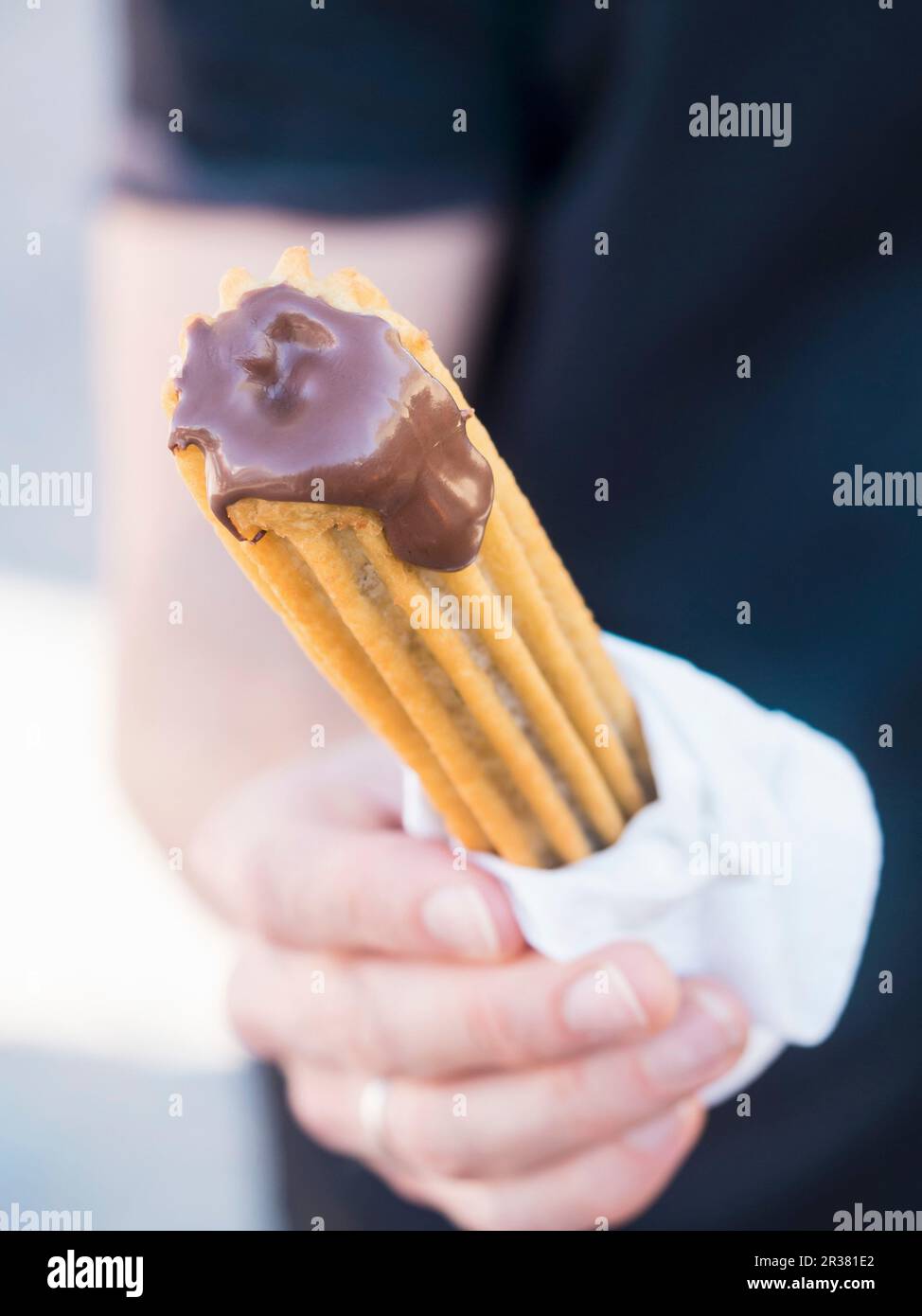 A person holding a churro in their hand Stock Photo - Alamy
