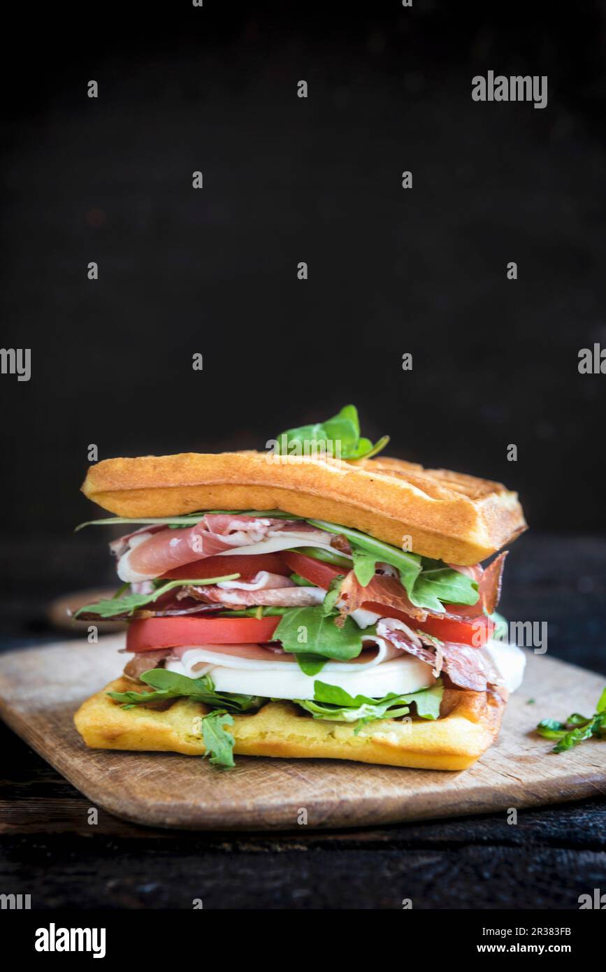 A waffle sandwich with ham, tomato, mozzarella and rocket Stock Photo ...
