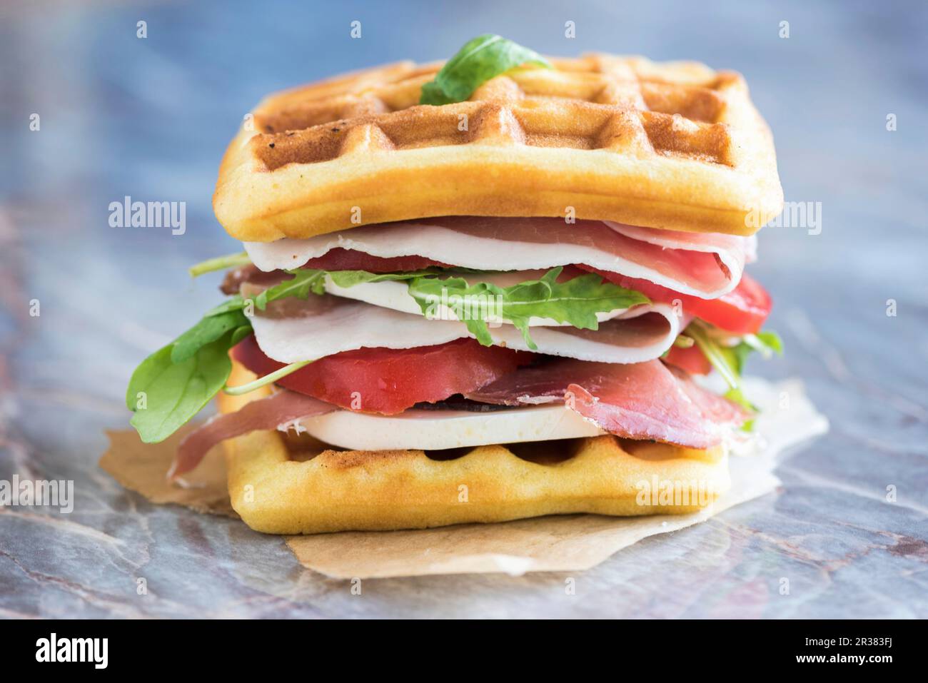 A waffle sandwich with ham, tomato, mozzarella and rocket Stock Photo ...