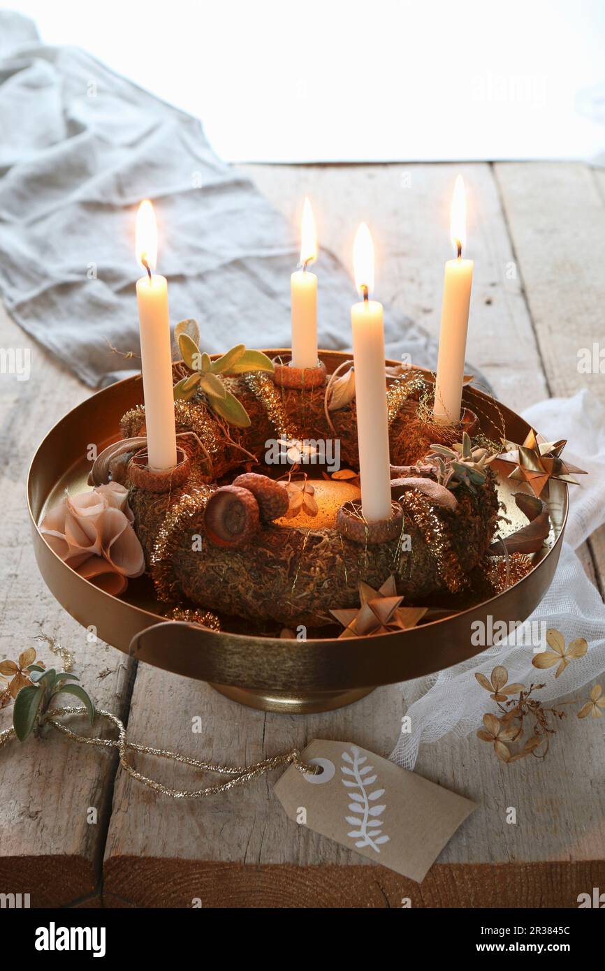 A traditional advent wreath on a golden stand with a hand painted label ...