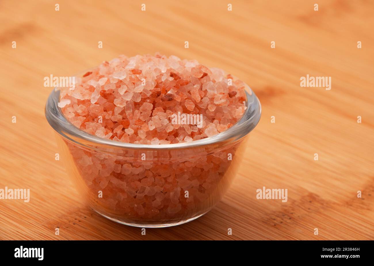 Himalayan pink salt in tiny transparent glass bowl on wooden bamboo ...