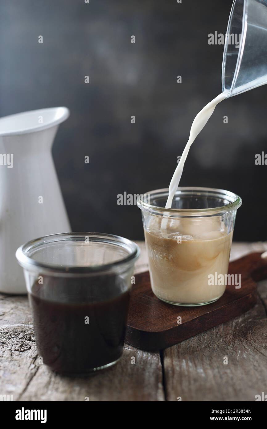 Milk being poured into coffee Stock Photo - Alamy