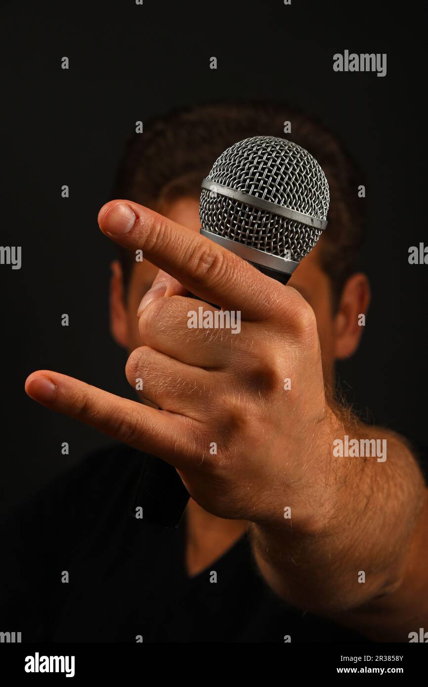 Hand with microphone and devil horns isolated on black Stock Photo - Alamy
