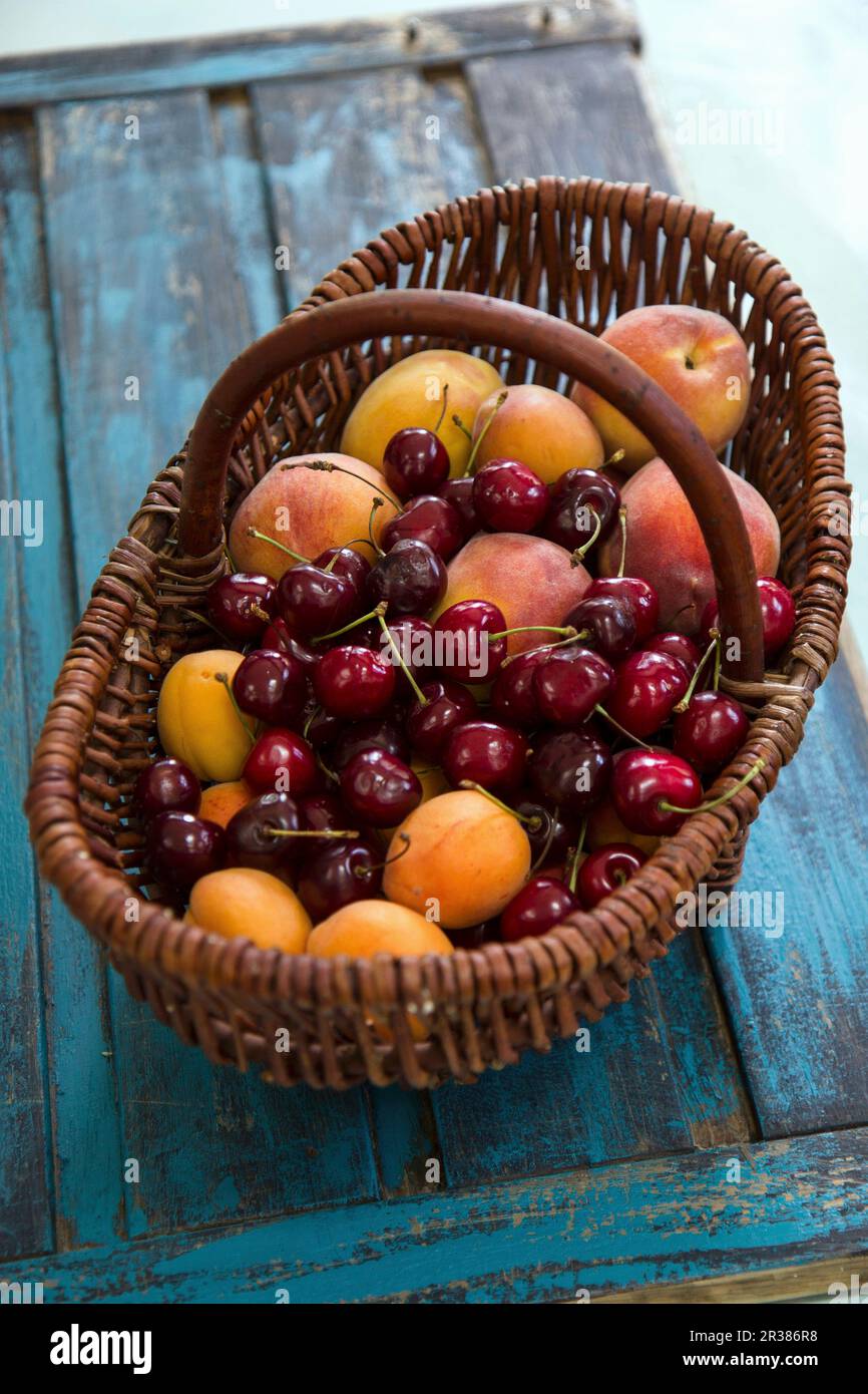 Fresh apricots, peaches and cherries in a basket Stock Photo - Alamy