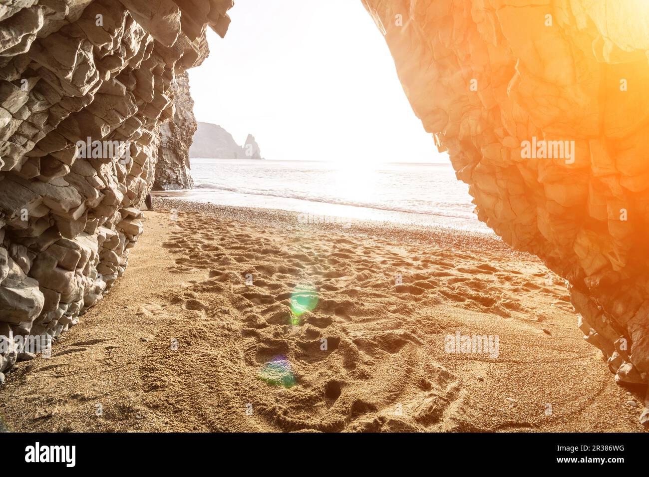 sunset seascape, captured from a rocky volcanic cave, view of the beach ...