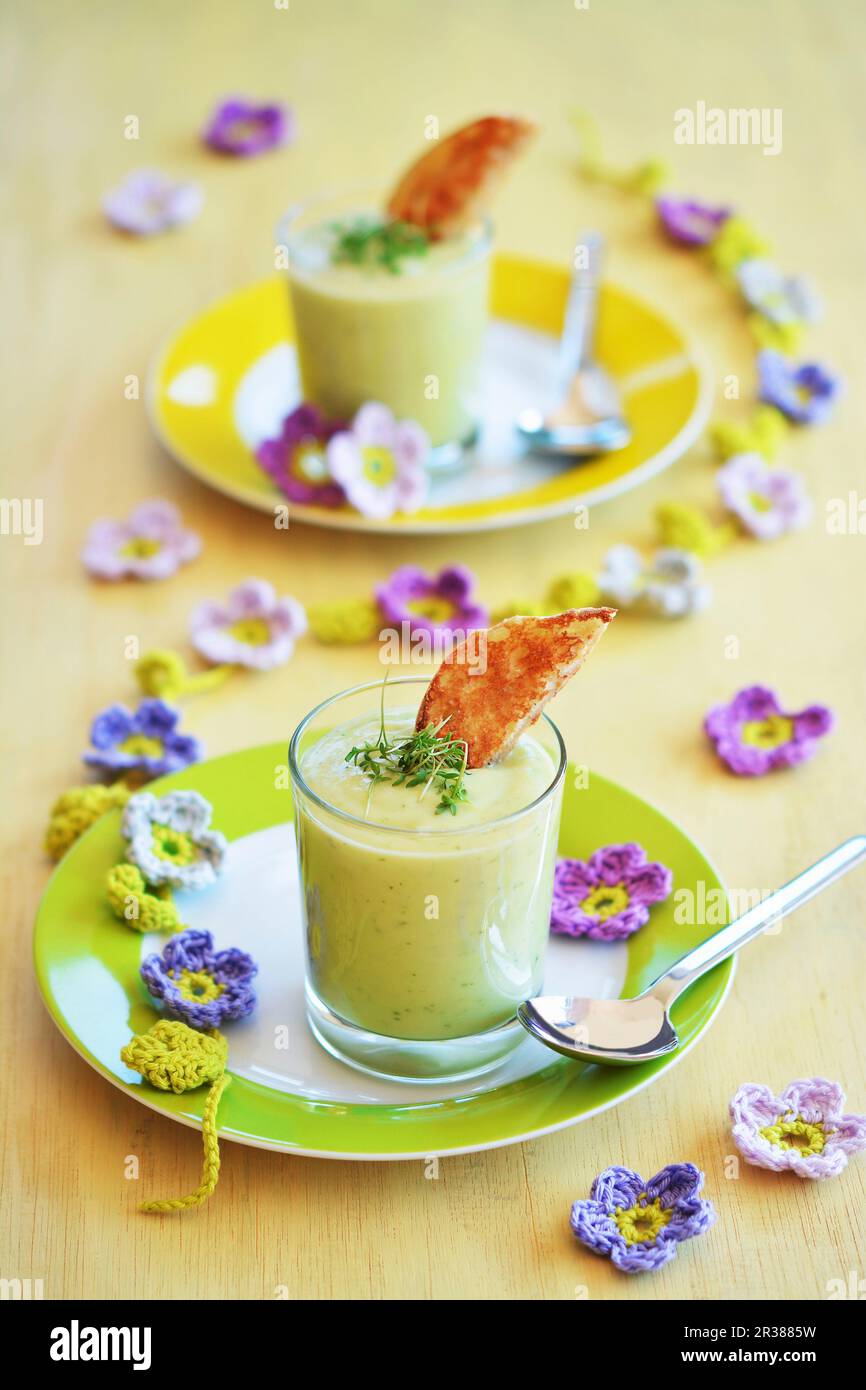 Avocado soup in two glasses with toast and fresh cress, and decorative crochet spring flowers ...