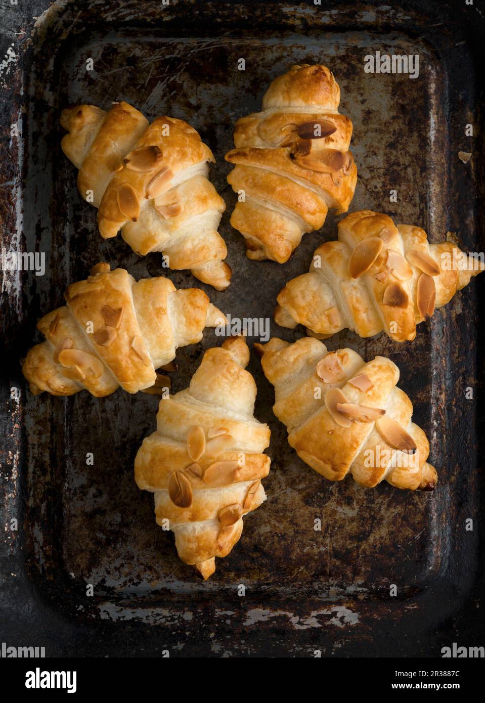 Croissants with almond flakes on a baking sheet Stock Photo - Alamy