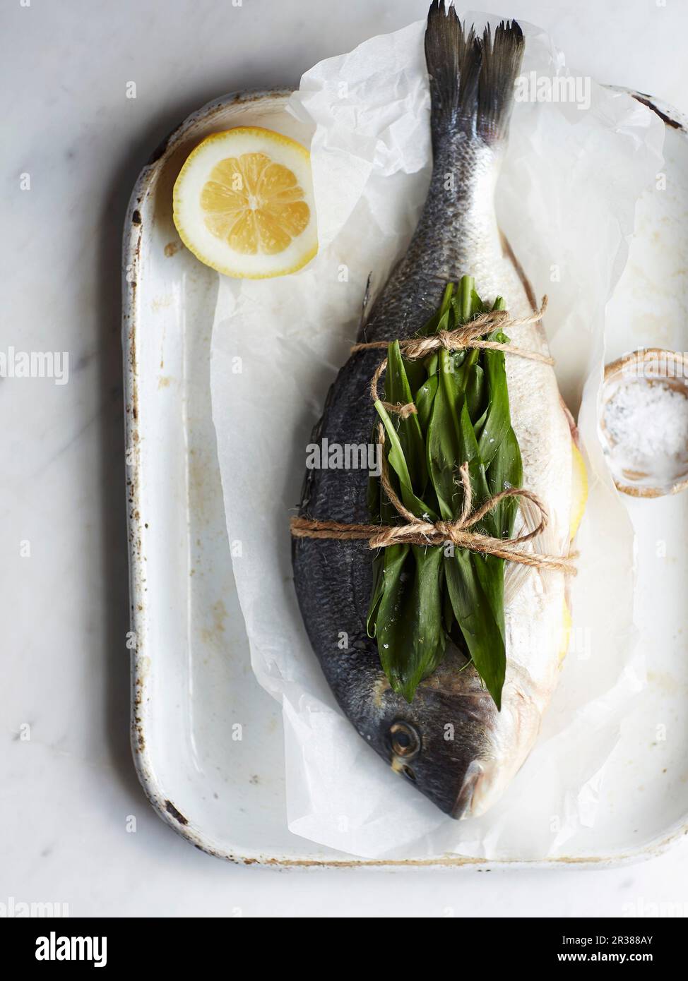 A whole sea bream with wild garlic on baking paper Stock Photo - Alamy