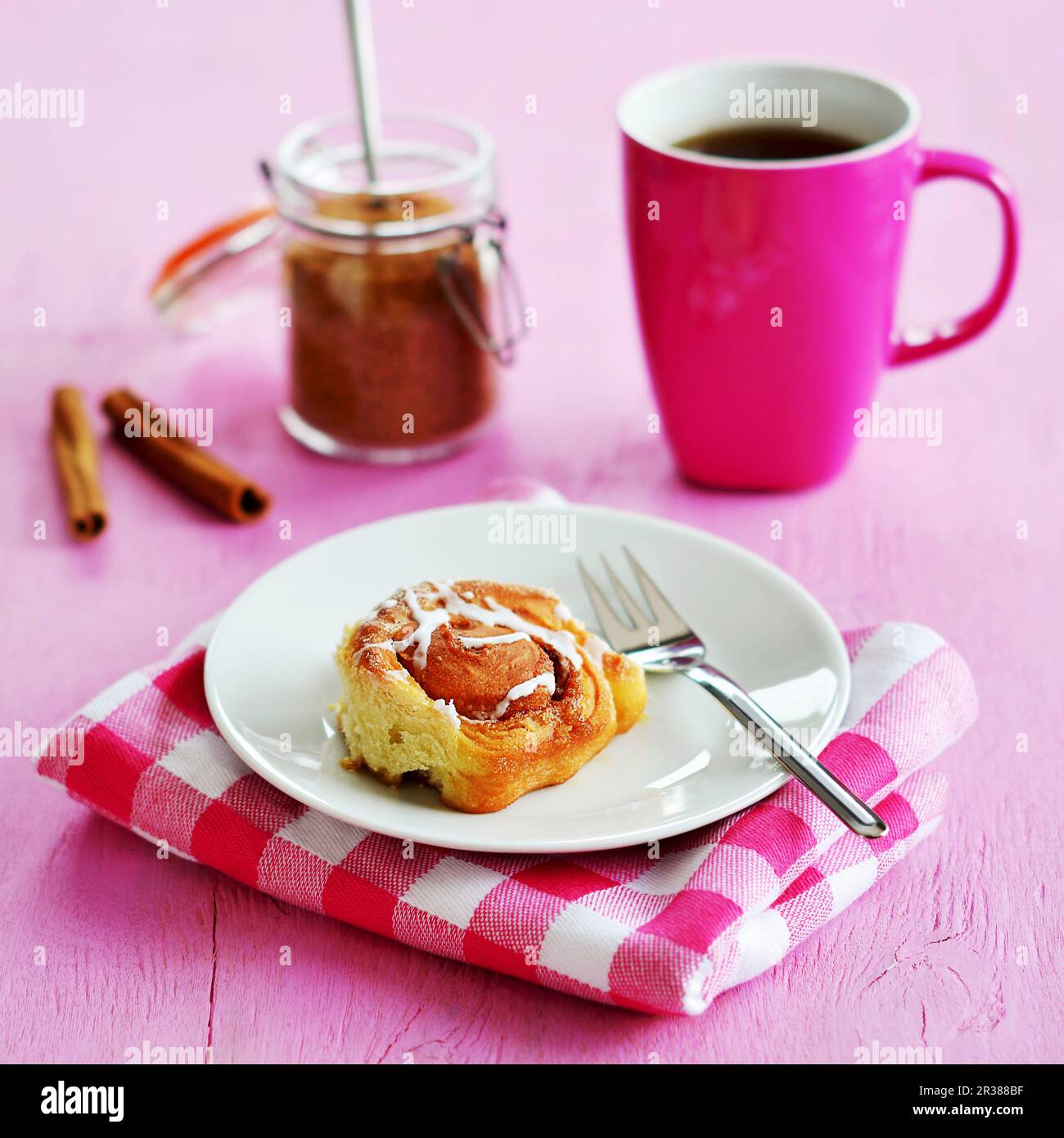 A cinnamon roll served with tea Stock Photo - Alamy