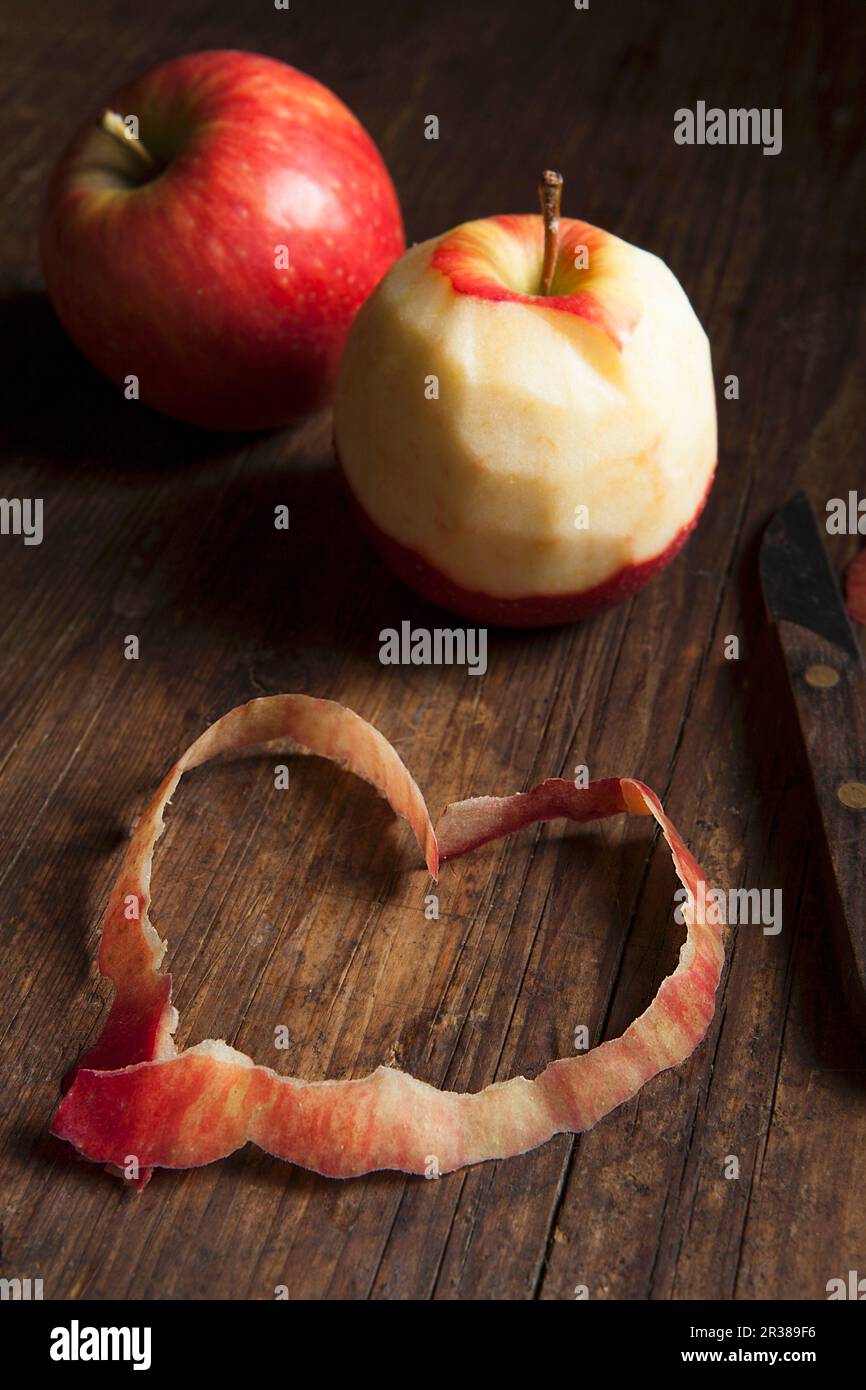 Two whole apples, one peeled, and a heart made out of the peelings ...