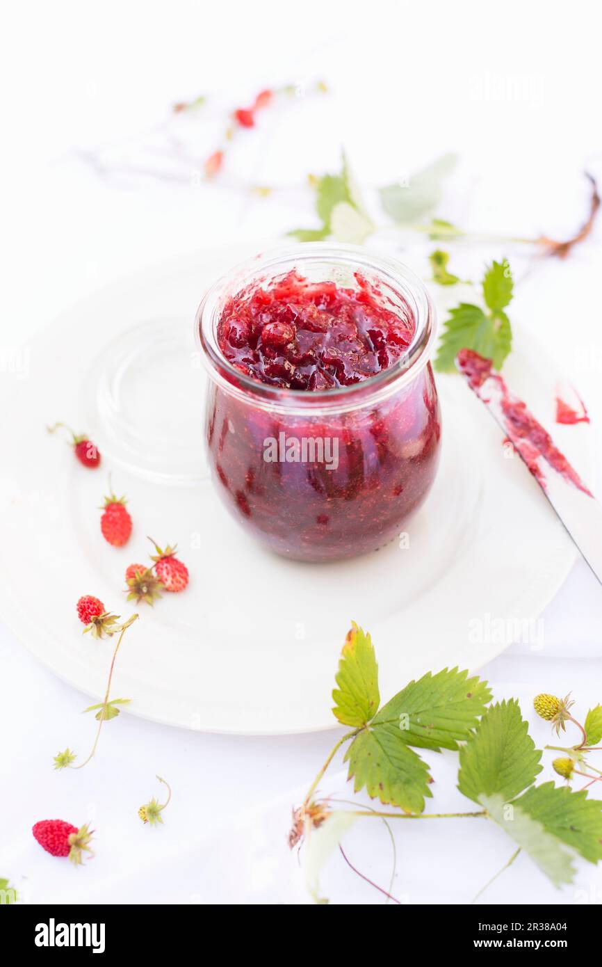 Homemade wild strawberry jam in a preserving jar with fresh berries and ...
