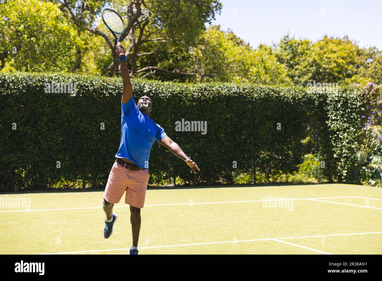 Happy senior african american man playing tennis reaching with racket ...