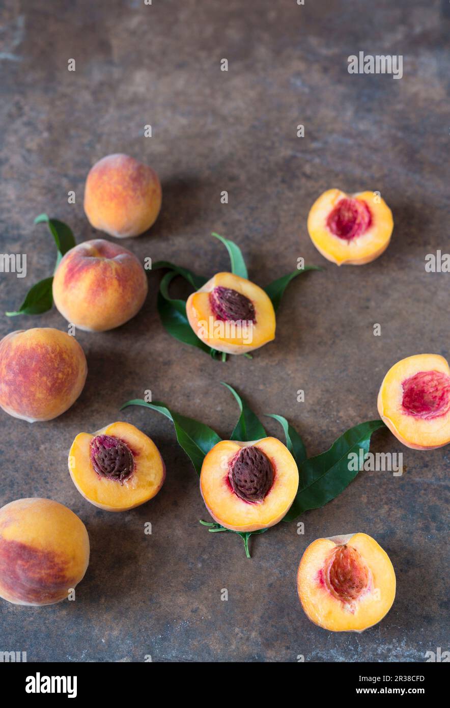 Peaches and peach halves on a metal surface Stock Photo - Alamy