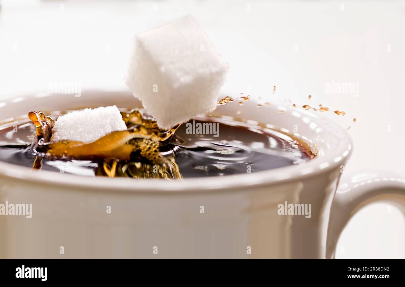 Sugar lumps falling into a cup of coffee Stock Photo - Alamy