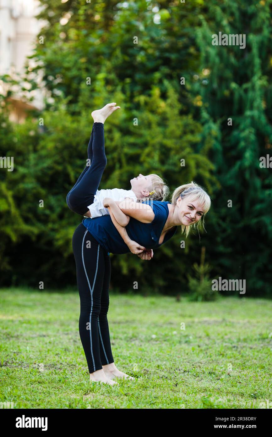 Mother and daughter doing yoga exercise outdoors. Happy family Stock ...