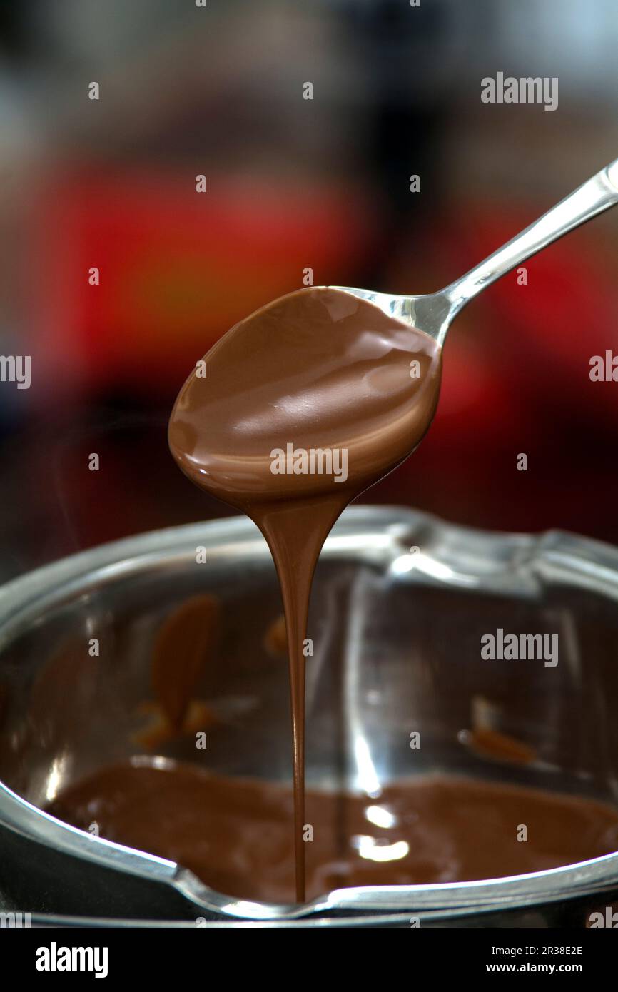 Melted chocolate dripping from a spoon into a bowl Stock Photo - Alamy